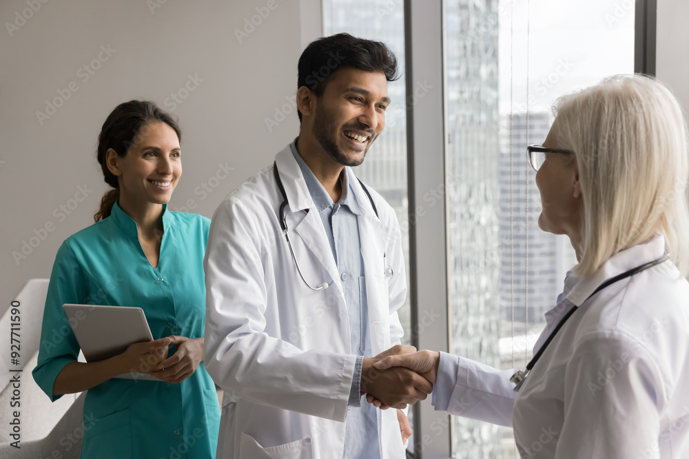 Young male intern wear white coat shaking hands with middle-aged ...