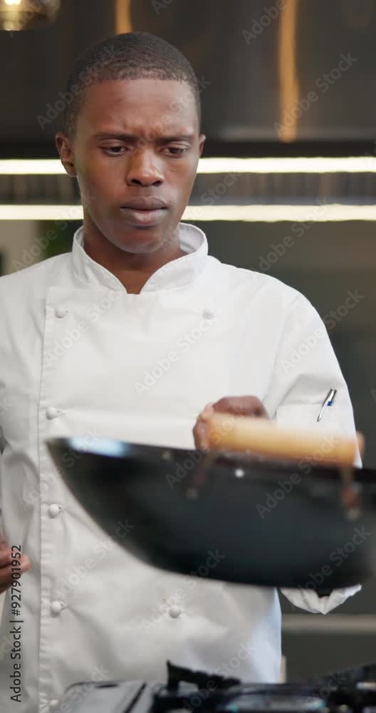 Black man, chef and cooking food in kitchen with pan on fire, speed and ...