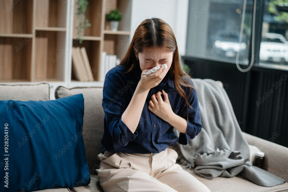 Young Asian woman suffering from flu symptoms, covered with a blanket ...