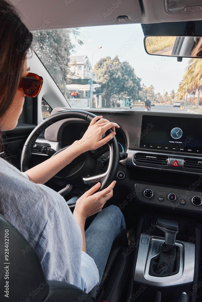 Woman driving car, hands on steering wheel, eyes on infotainment screen ...