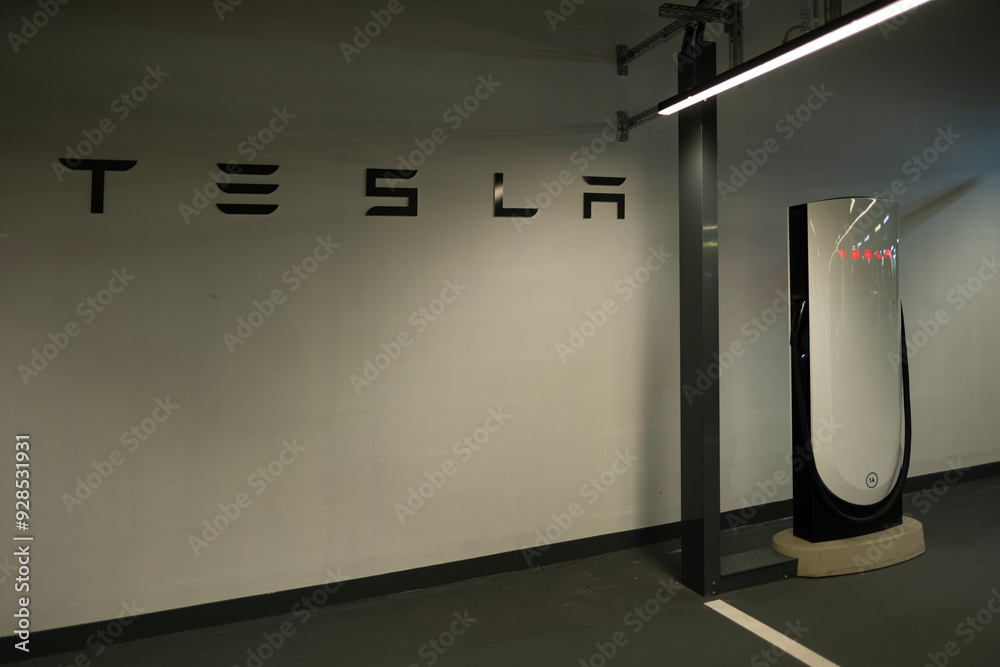 Tesla Supercharger sign stands tall against backdrop urban construction ...