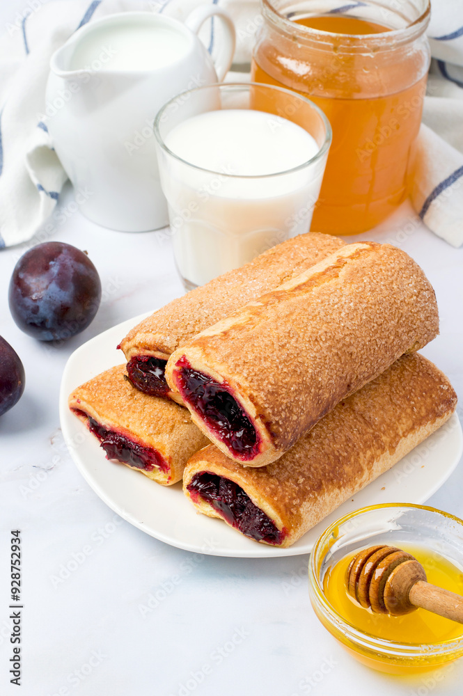 Plum strudel, fresh plums, glass of milk and honey on a light ...