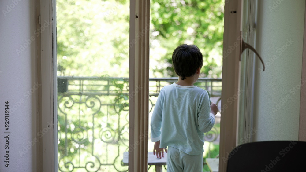 Young boy reaching for the window knob, stepping out onto the balcony ...