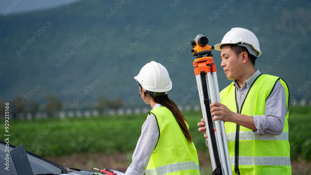 Survey team is working with a theodolite and road construction plans ...