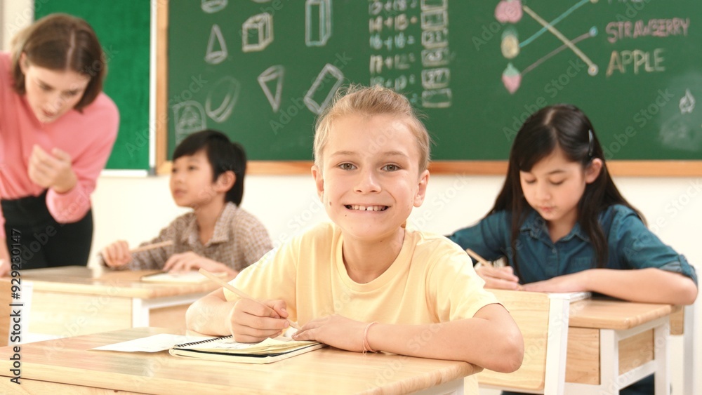 Caucasian smart child smiling at camera while doing classwork at ...