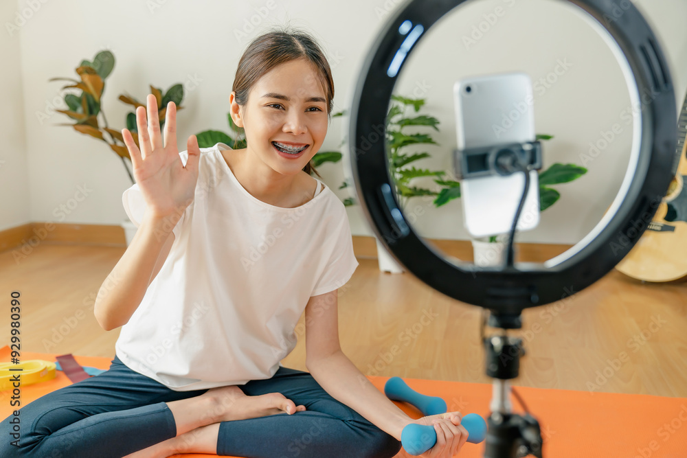 Woman fitness trainer exercising while vlogging on smartphone at home ...
