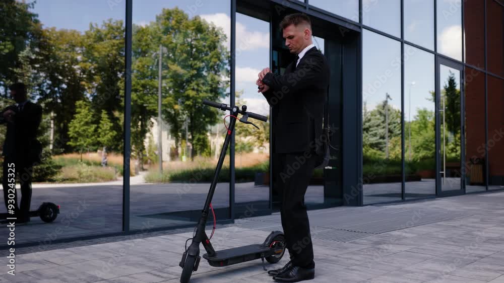 A businessman dressed in a black suit and tie is exiting a modern glass ...