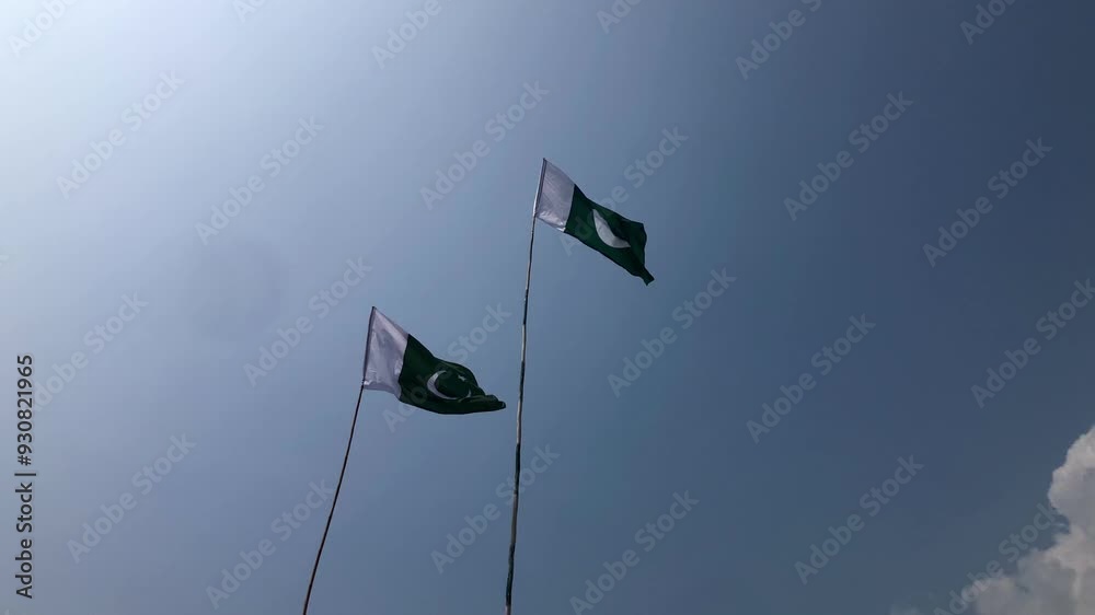 4K video of two Pakistani flags waving against a clear blue sky. The ...