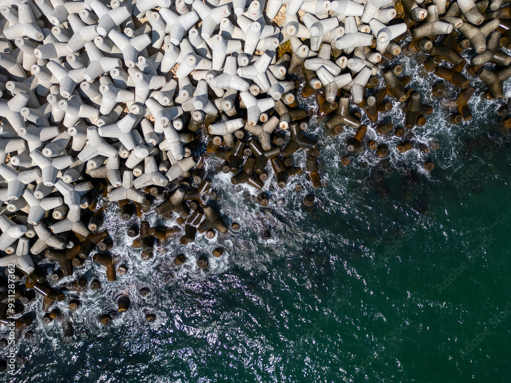Aerial view of concrete tetrapod wave breakers along a rugged shoreline ...