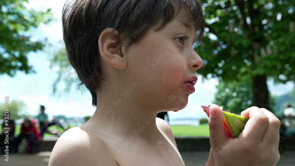 Side profile of young boy eating watermelon, shirtless and enjoying a ...