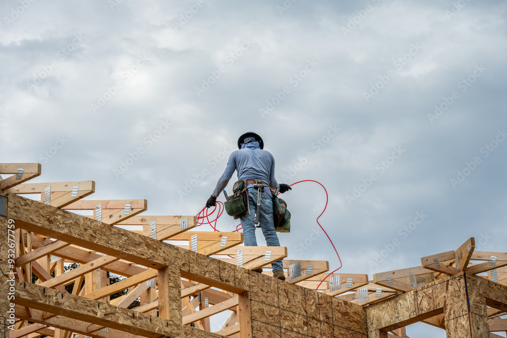 New residential home construction in framing stage, workman with ...