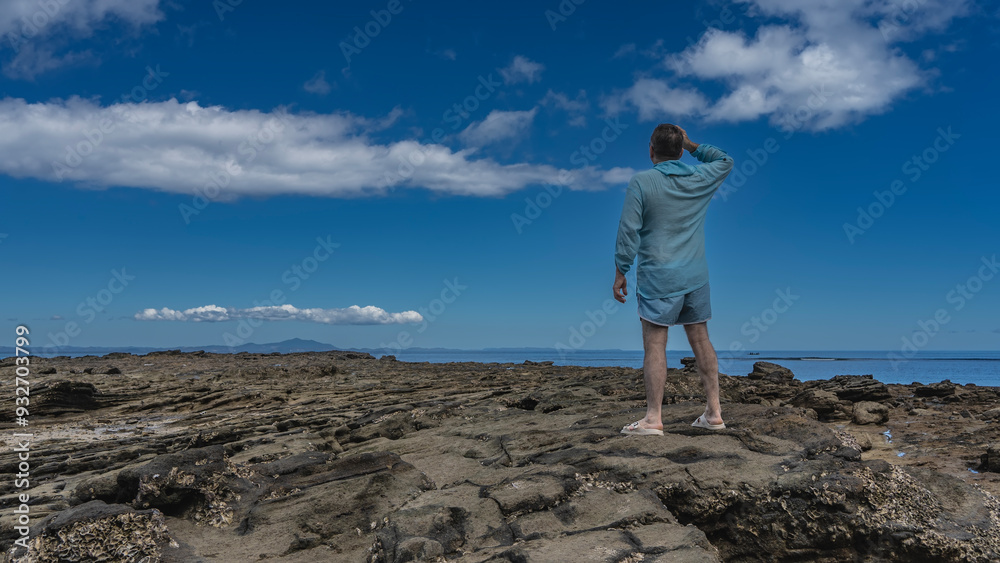 The time of low tide in the ocean. A man stands on exposed rocks ...