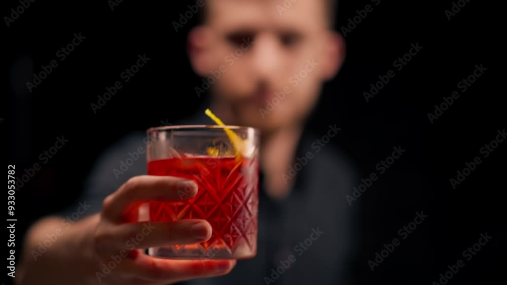 close up in a bar on a black background handsome young bartender in a ...
