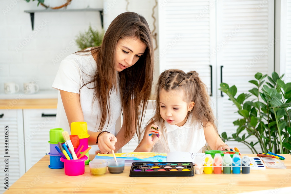 mom and a drawing teacher teaches a little girl child to draw with ...