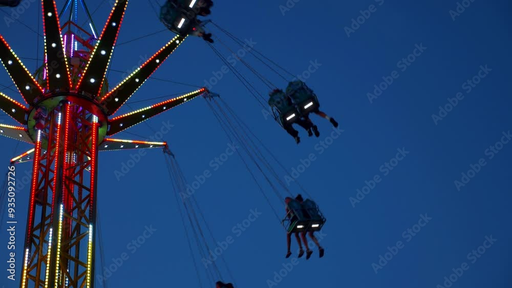 A vibrant amusement ride adorned with glowing lights against the night ...