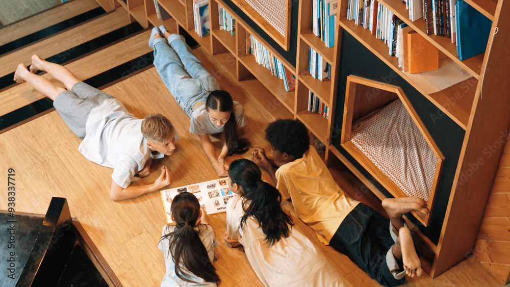 Group of diverse children lying down in circle while reading a book at ...