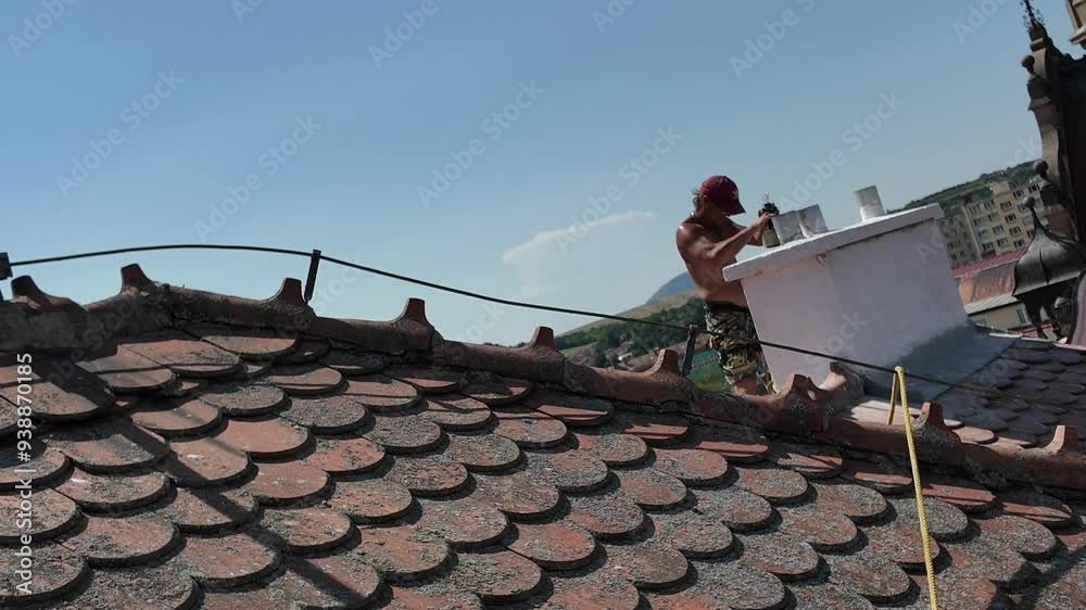 A worker fixes a chimney on the roof. A worker mends the roof. Worker ...