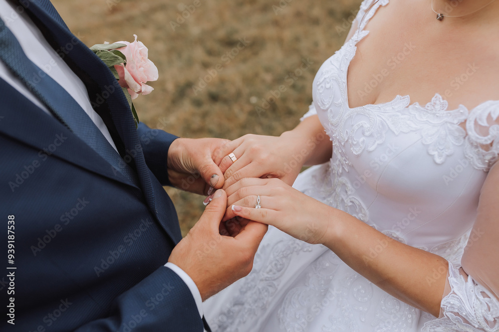 A bride and groom are getting married and the bride is wearing a white ...