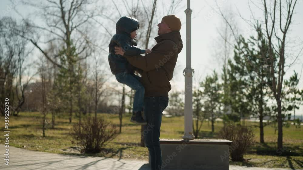 A close-up of father lifting up his son both are dressed in jeans and ...