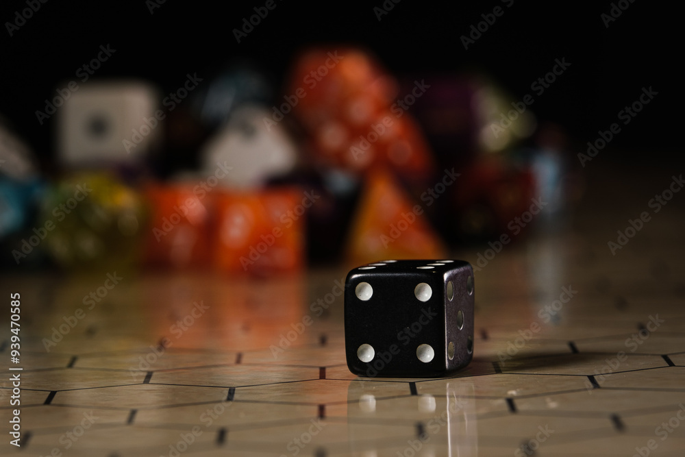 a black six-sided D6 dice with white dots, showing four dots, sitting ...