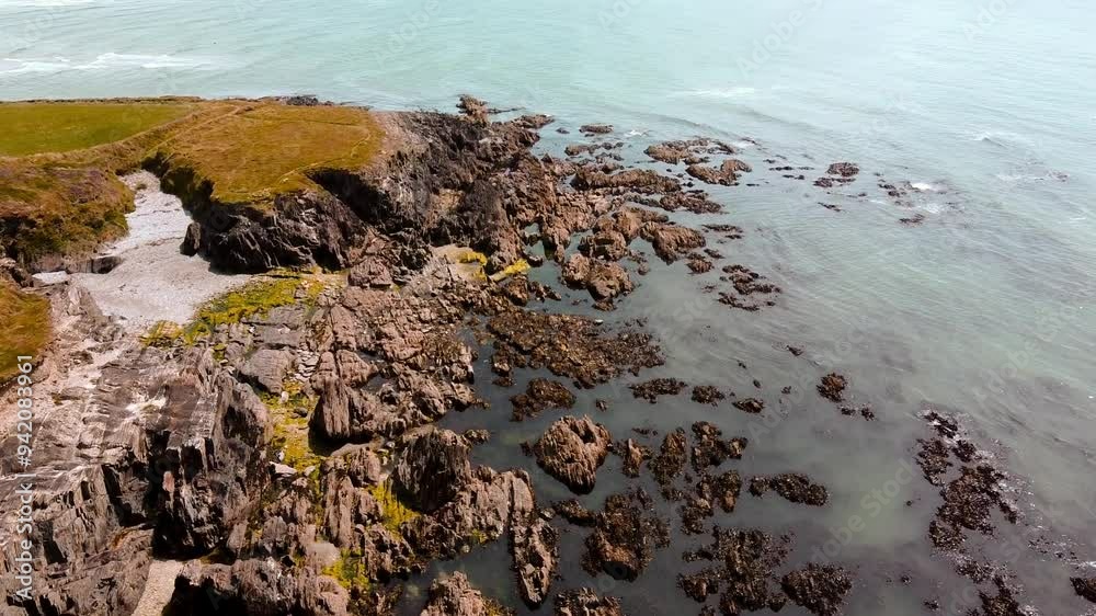 Coastal cliffs reveal rocky terrain and tidal pools as the tide recedes ...