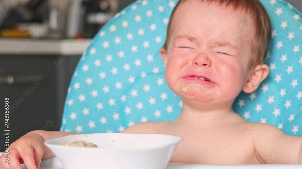 cute hungry baby toddler boy eating in highchair in kitchen.child is ...