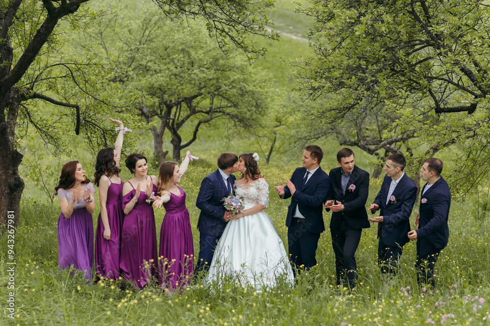 A group of people are posing for a picture in a field. The bride and ...