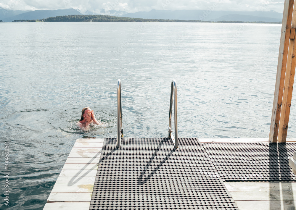 Swimming teen boy into the cold Fjord water next to Scandinavian ...