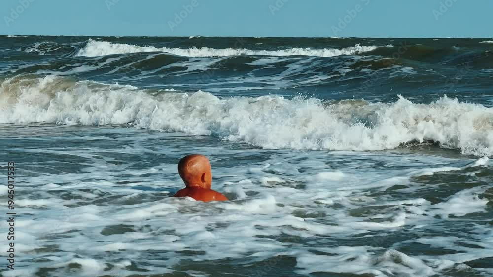 A child swims in the Sea of Azov. A boy jumps into the sea waves from ...