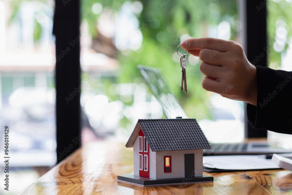 The real estate broker is handing over the house keys to the customer ...