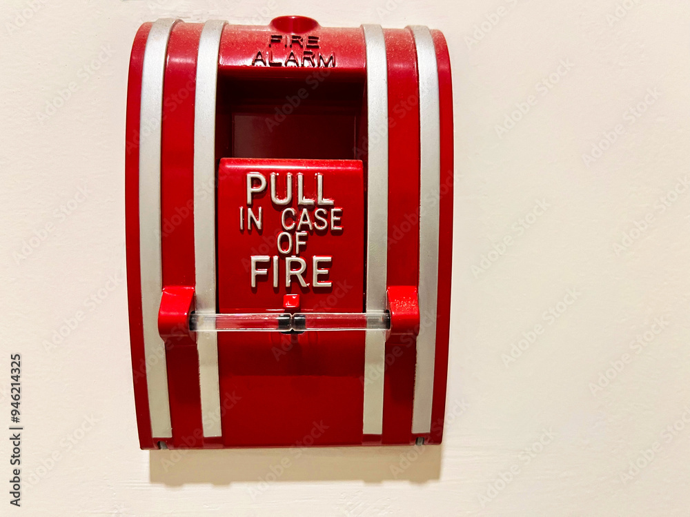 a vibrant red fire alarm mounted on a white wall, featuring a clear ...