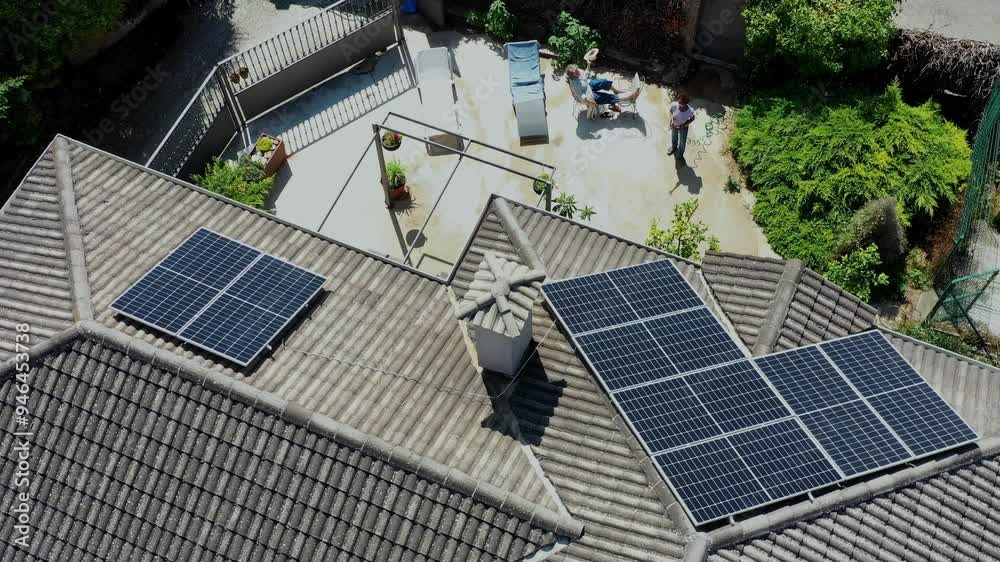 An aerial view shows solar panels on a rooftop and two women in a sunny ...