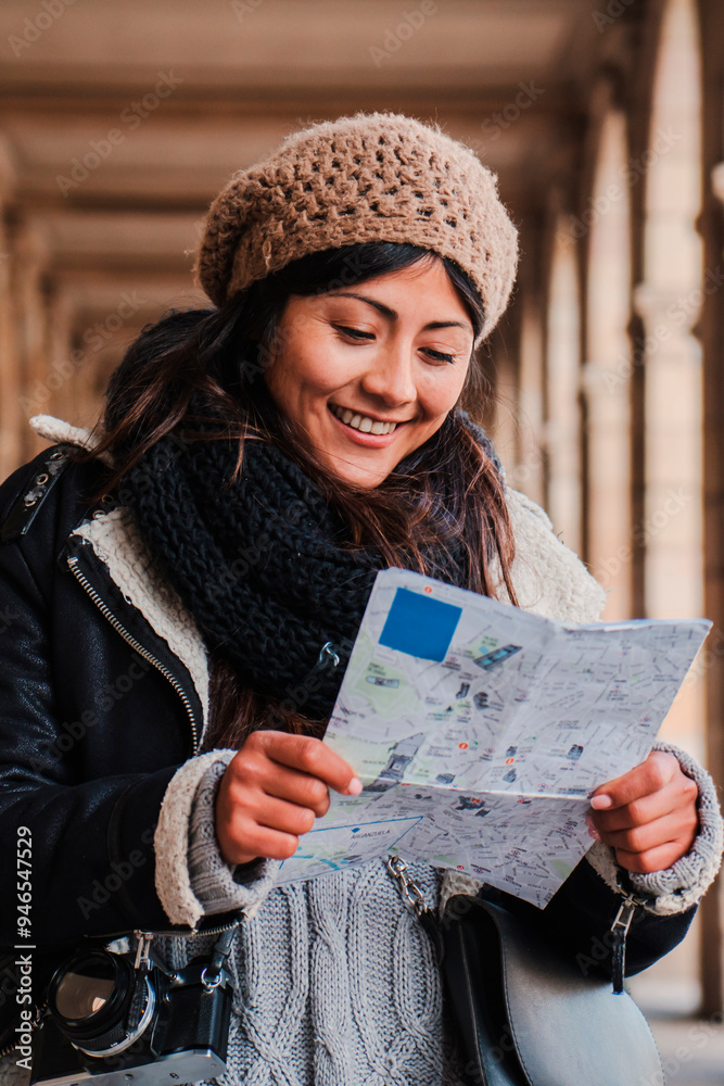 Vertical. Young tourist woman smiling and reading a map to find the ...