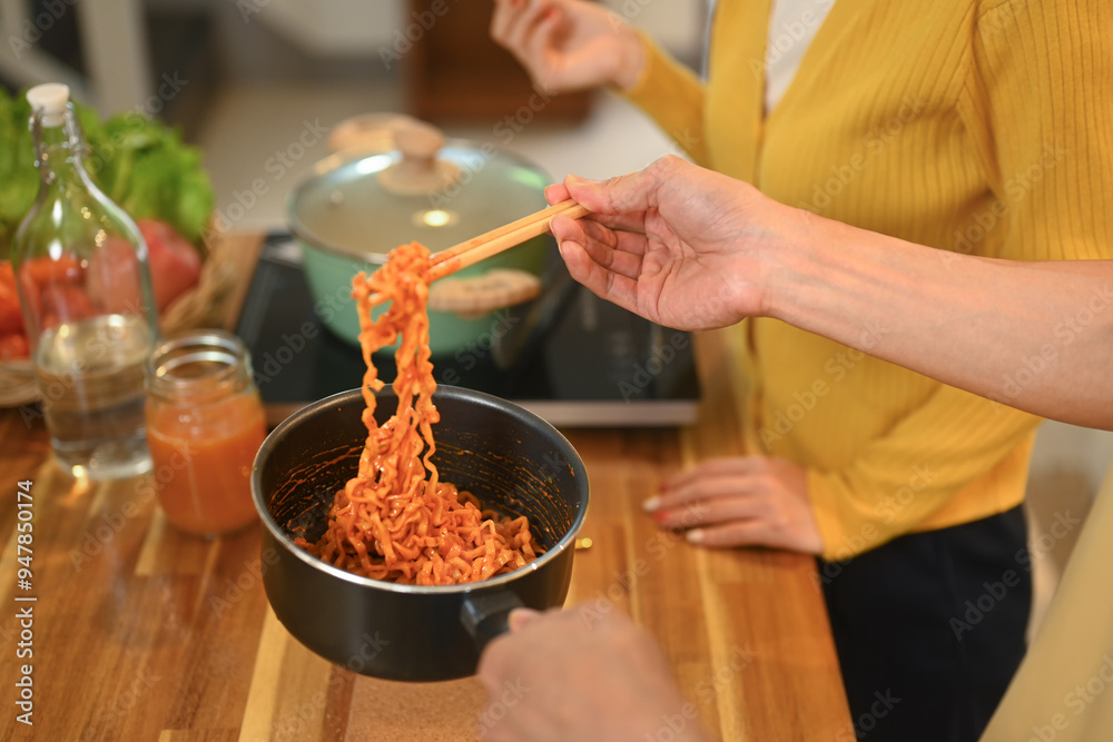 Close up shot of young couple sharing a bowl of instant noodles ...