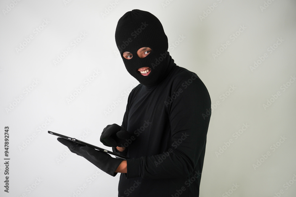 Young Adult black masked robber is holding digital tablet with blank ...