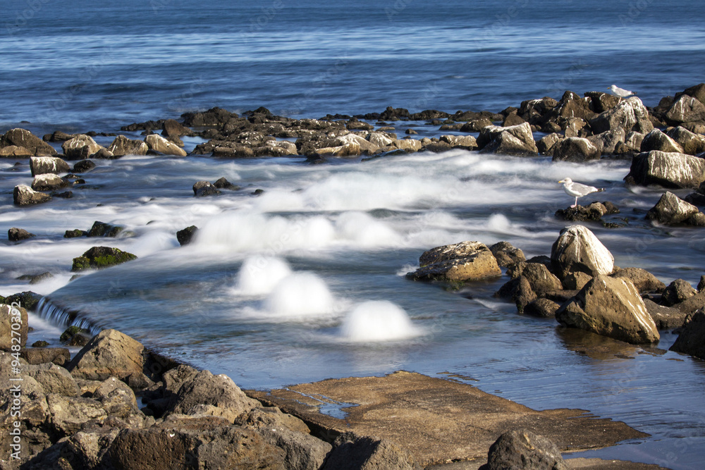 Long exposure view of water eruption with white bubble and seagulls on ...