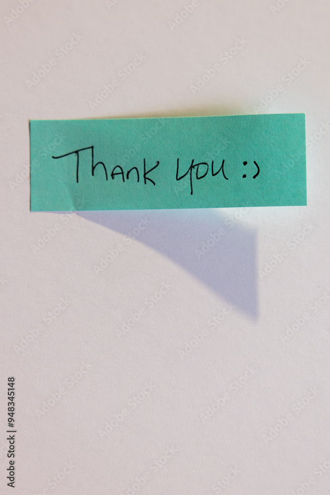 A blue sticky note with the words "thank you" written on it. The note ...