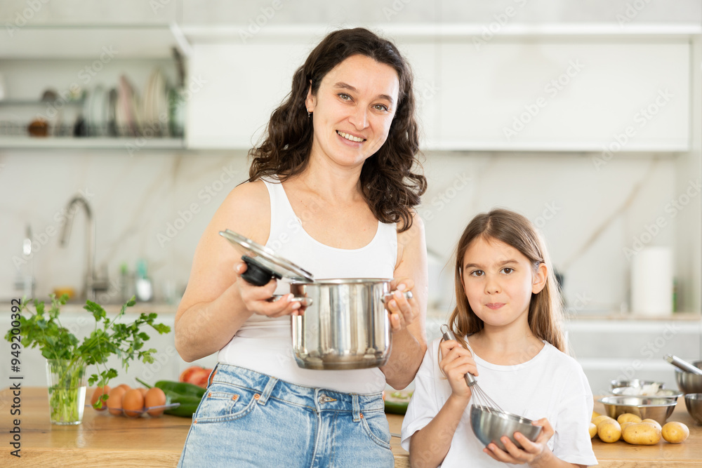 Woman and her daughter pose in kitchen with dishes in their hands. Mom ...