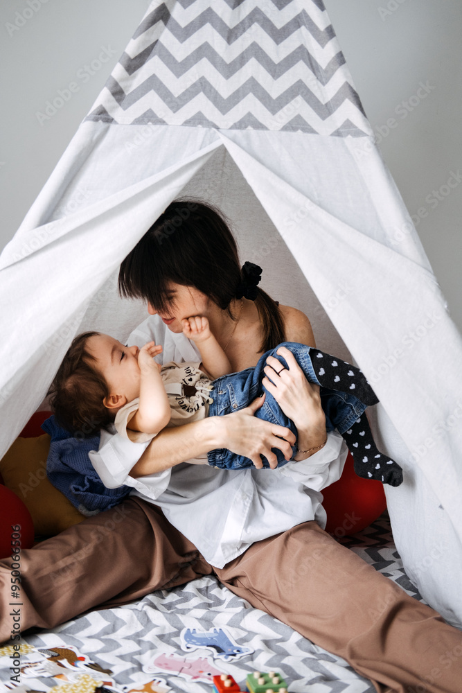 Mother and toddler playing together in a cozy indoor tent. Bonding ...