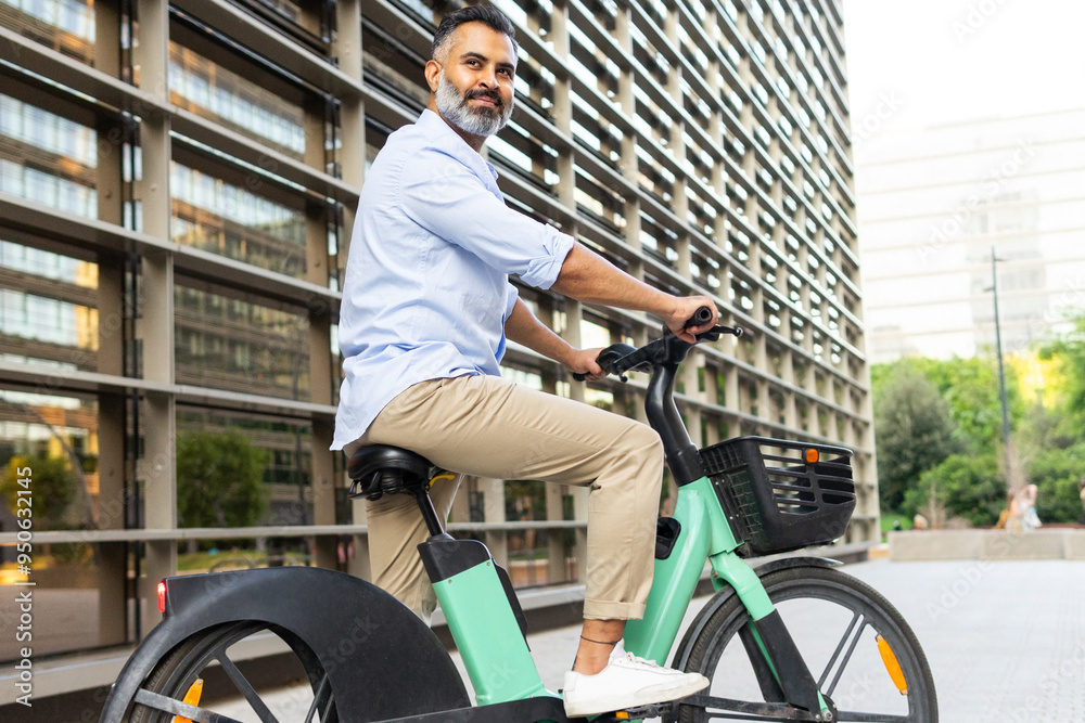 From below an Indian man commuting on electric bike in urban setting ...