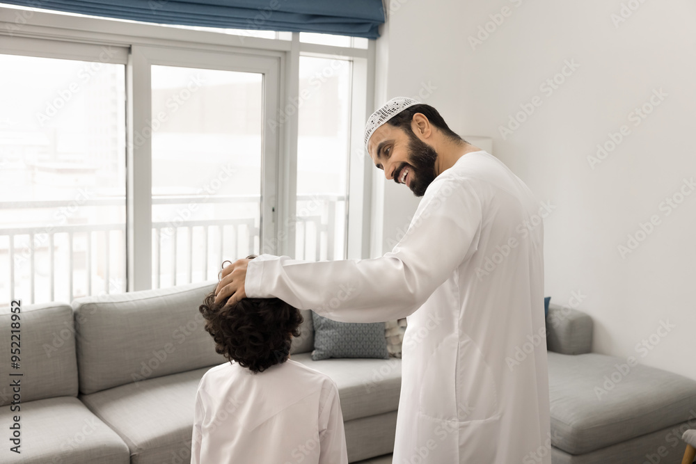 Positive Middle Eastern father in white Muslim Arabic dress cuddling ...