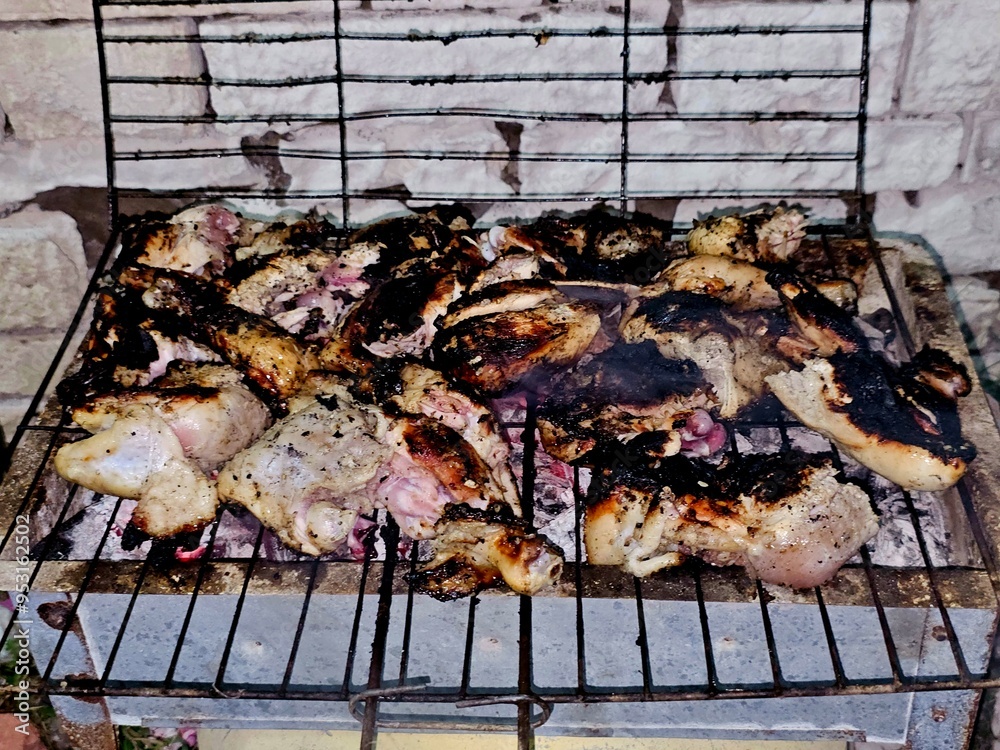 chicken quarters on a grid grilled and barbecued on charcoal flames ...