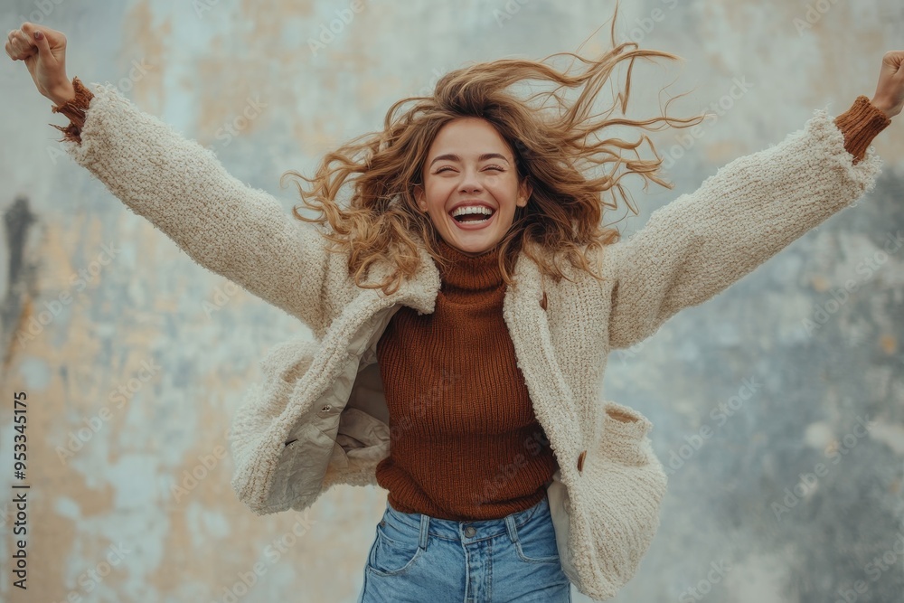 Joyful young lady jumping and raising arms in front of wall outside ...