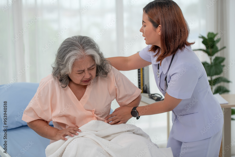 Asian nurse helping a senior Asian female patient with stomach ache on ...