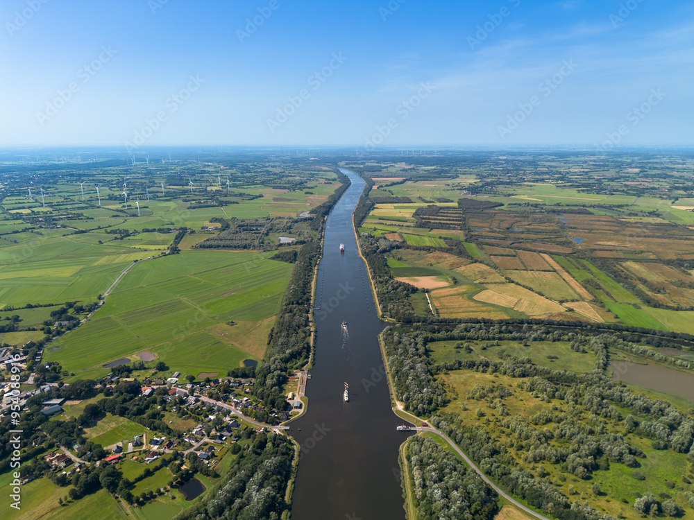 Aerial drone image of the Kiel canal, nord ostsee kanal, in Germany. Blue sky and green bank of ...