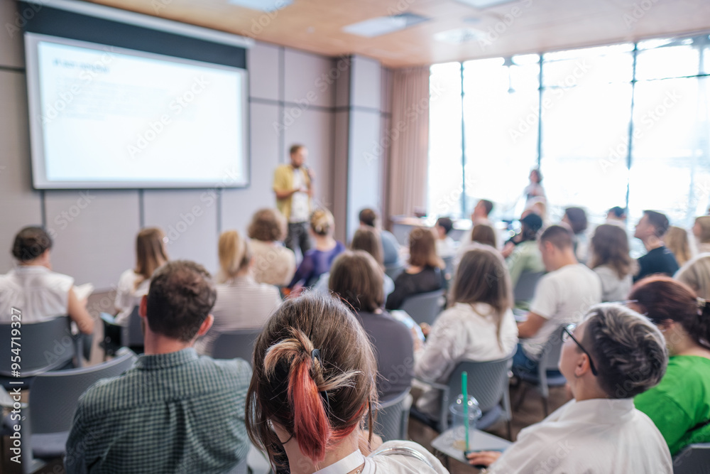 Group of people attending a presentation in a conference room. Speaker ...