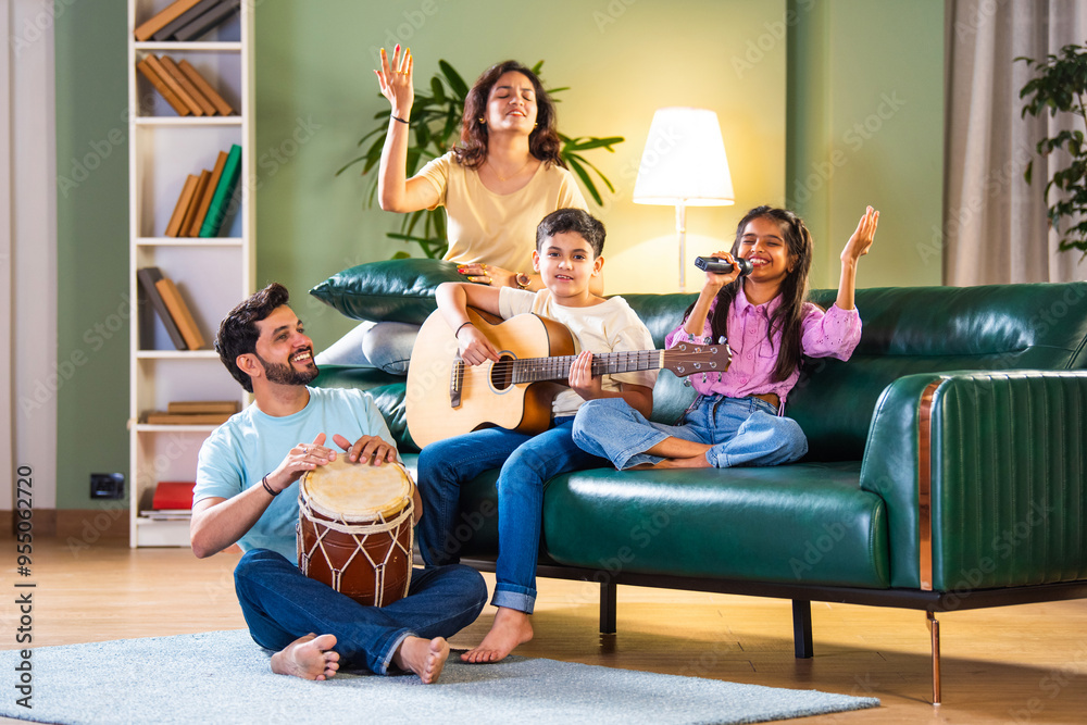 Happy Indian Asian family making music together at home; singing ...