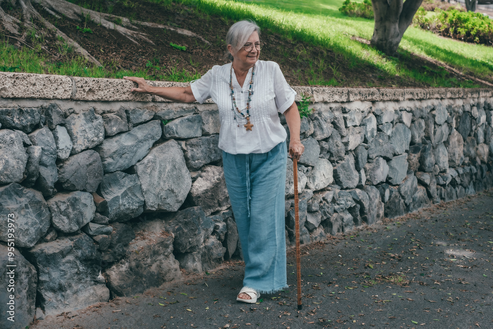 Smiling elderly 70s woman with walking disability holding knob of cane ...