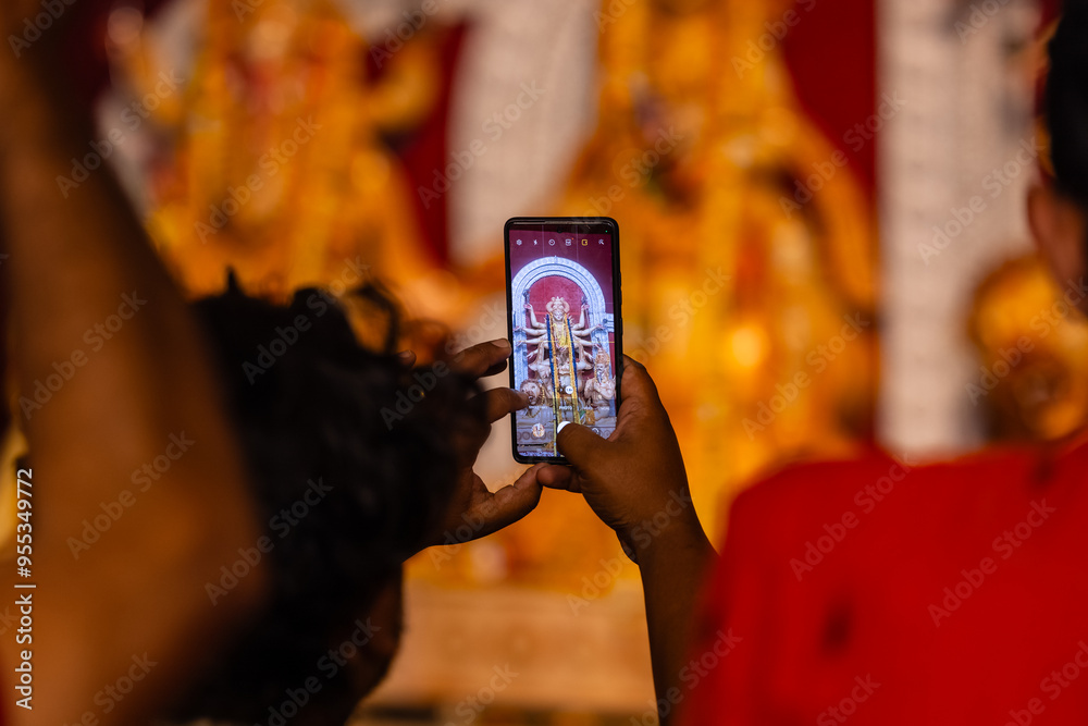 Hand holding mobile phone and taking photos of Goddess Durga idol at a ...