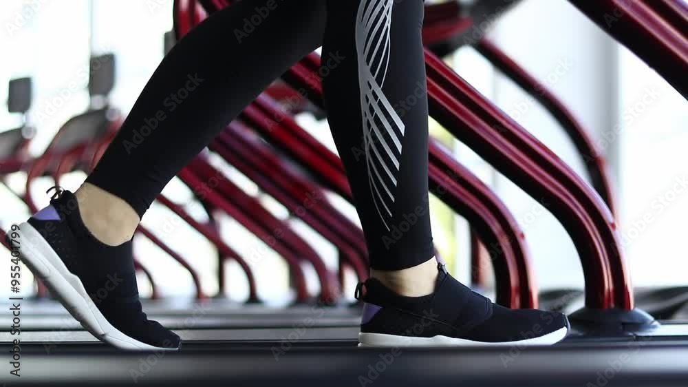 Treadmill in the gym. Side view of legs in sneakers walking on the ...